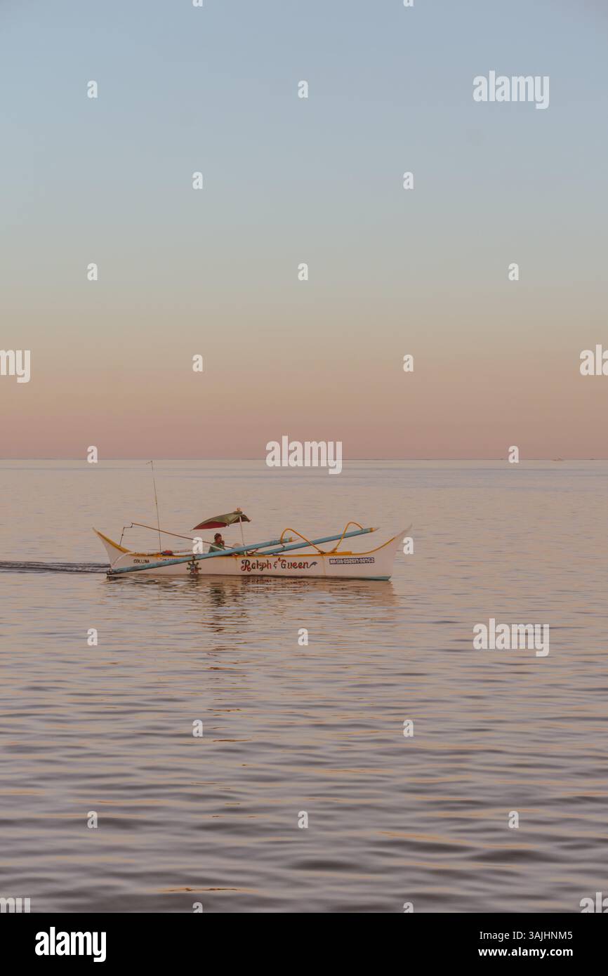 Traditional Filipino outrigger boat glides across serene waters at ...