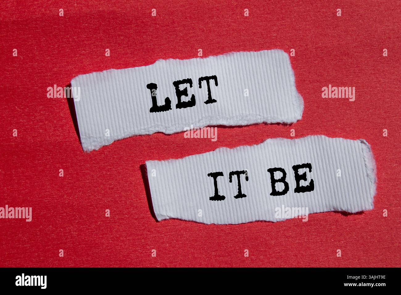 Let it be message written on ripped torn white paper pieces on red ...