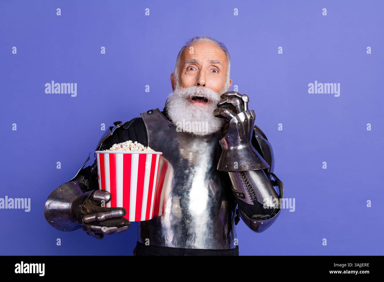 Bearded man in metallic medieval knight armor holding popcorn against ...