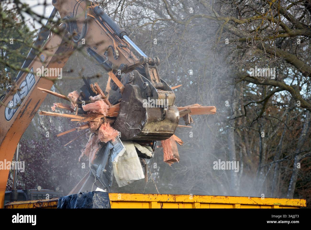 An excavator dumps a mixture of debris from a house teardown into an ...