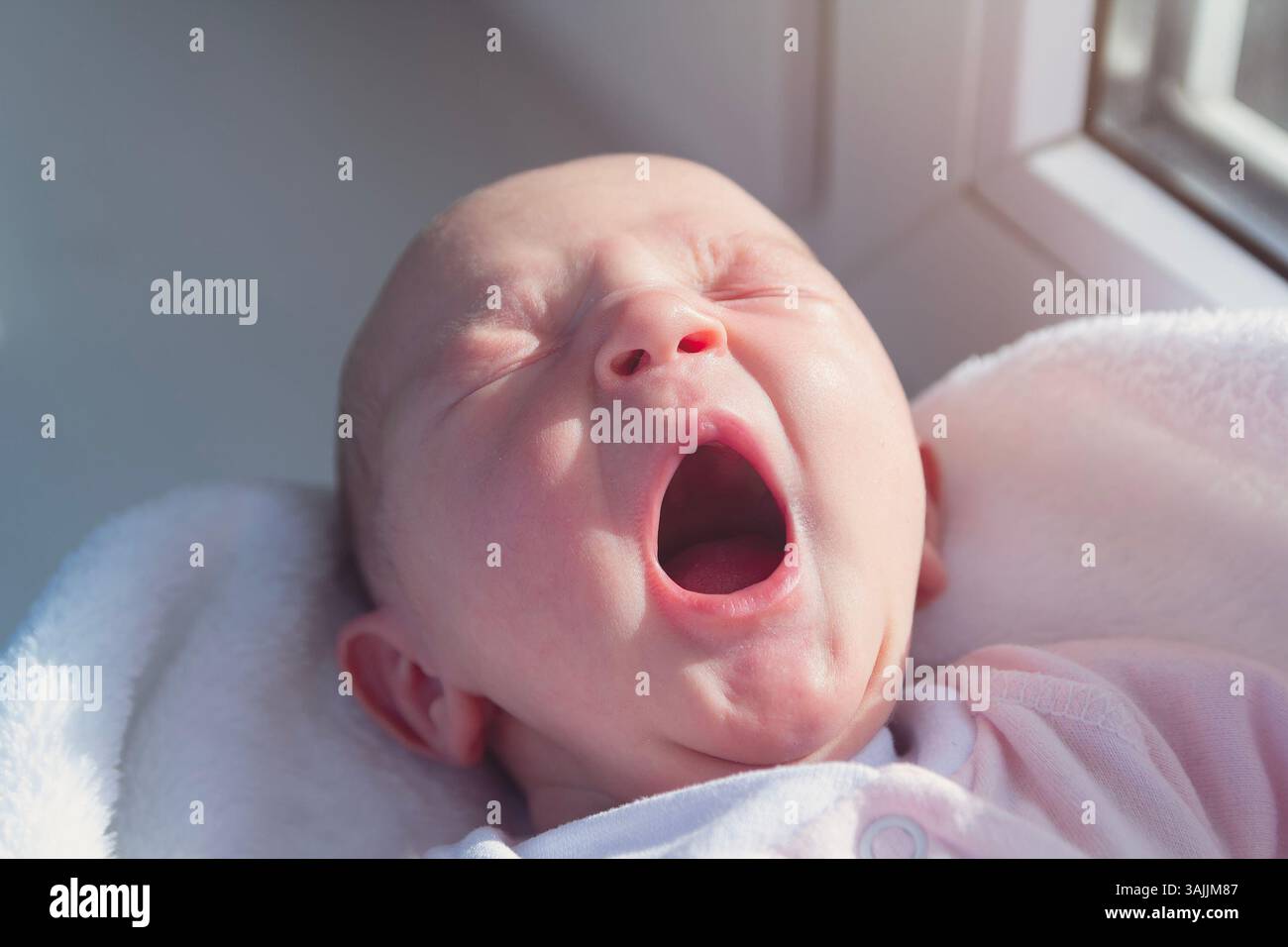 A newborn child yawns the sun -sanctified from the window. People Stock ...