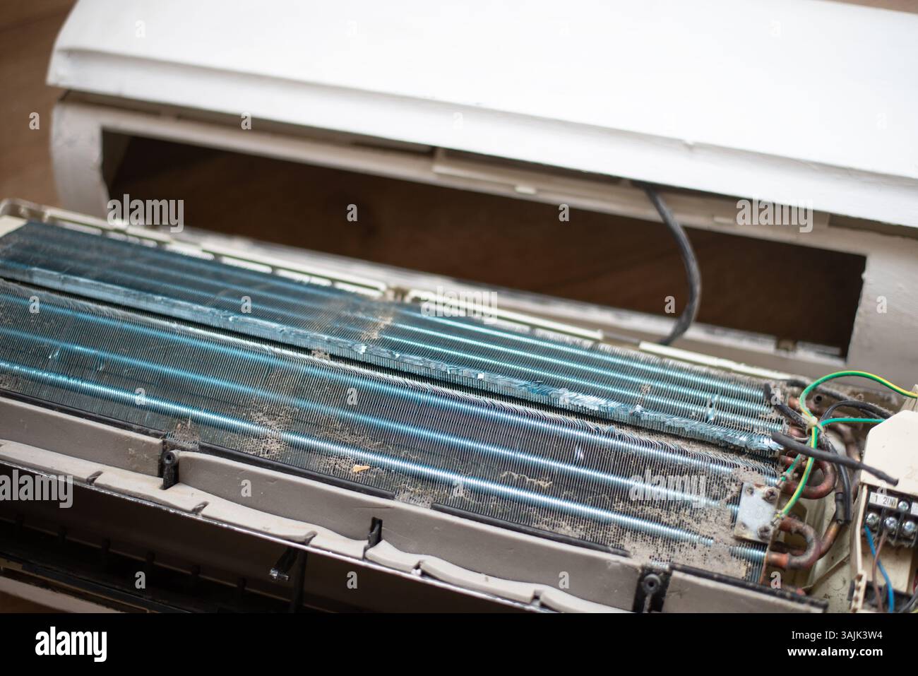 Dirty and disassembled wall-mounted air conditioner unit, showing internal components and dust ...