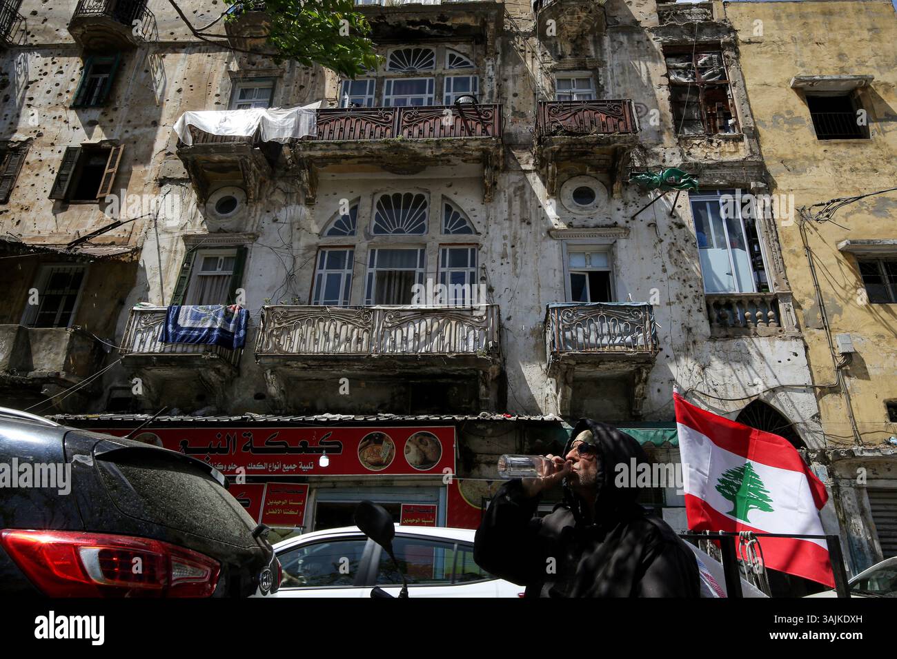 April 11, 2025, Beirut, Beirut, Lebanon: A man drinks water as he sits in front of a bullet ...