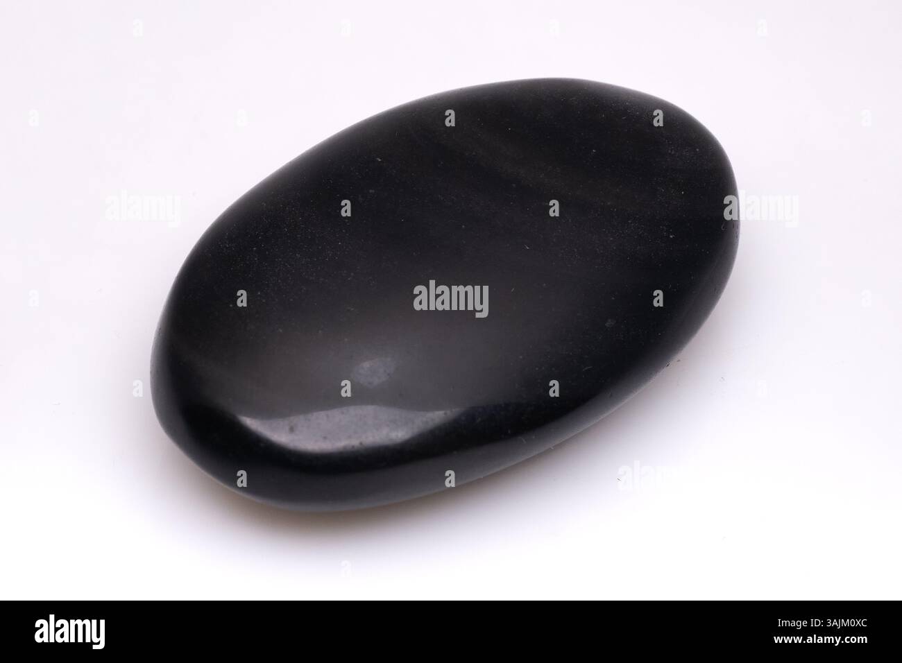 Polished black river stone isolated on a white background with subtle ...