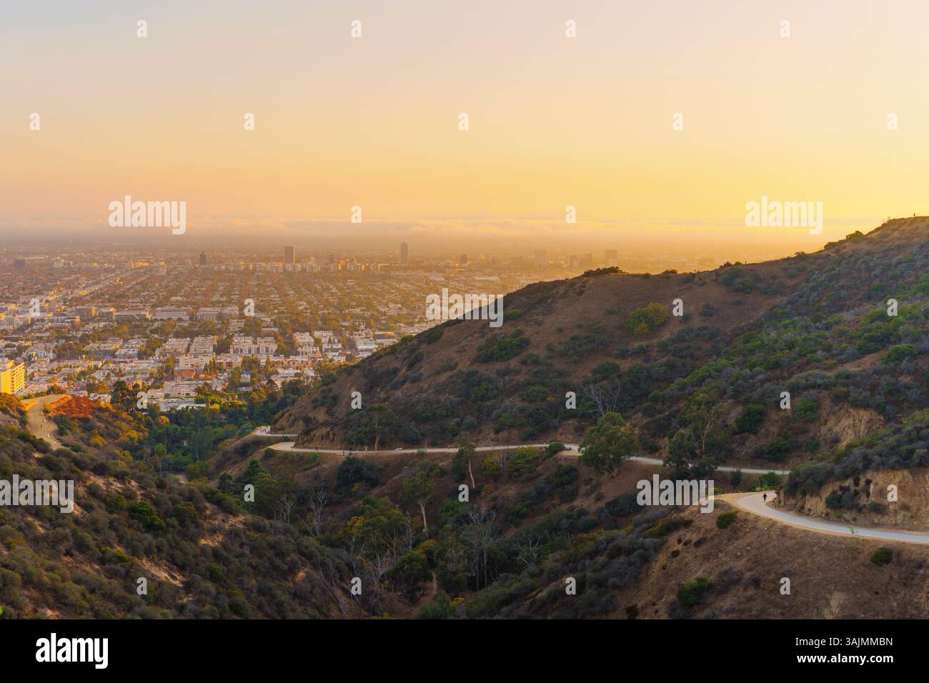 Hikers traverse winding trails at Runyon Canyon Park during golden hour ...