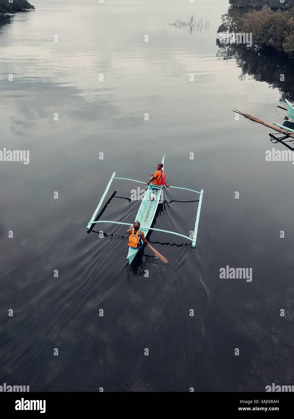 Aerial view of a traditional Filipino outrigger canoe paddled by two ...