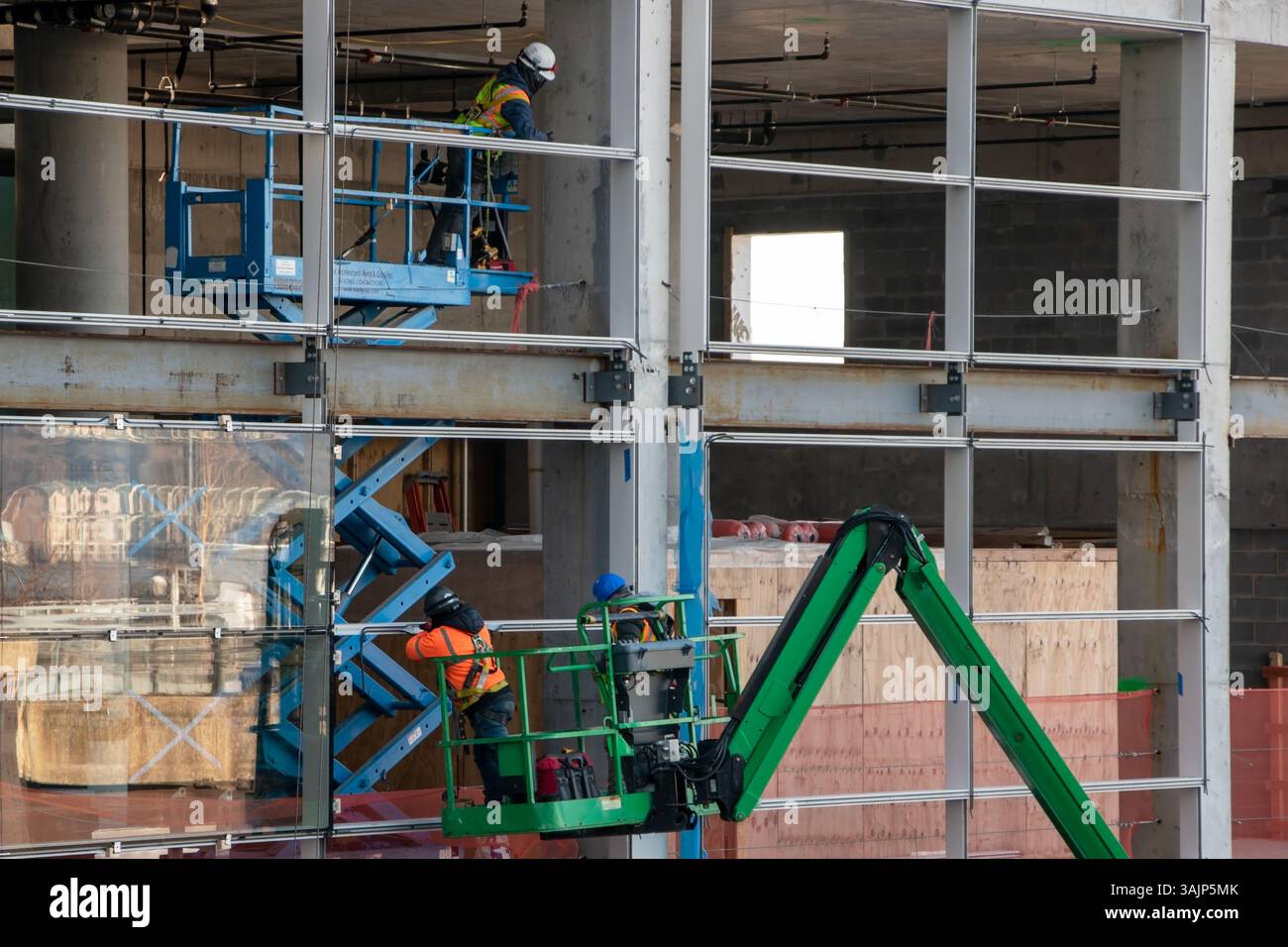 Team of builders working on a tall commercial building under ...