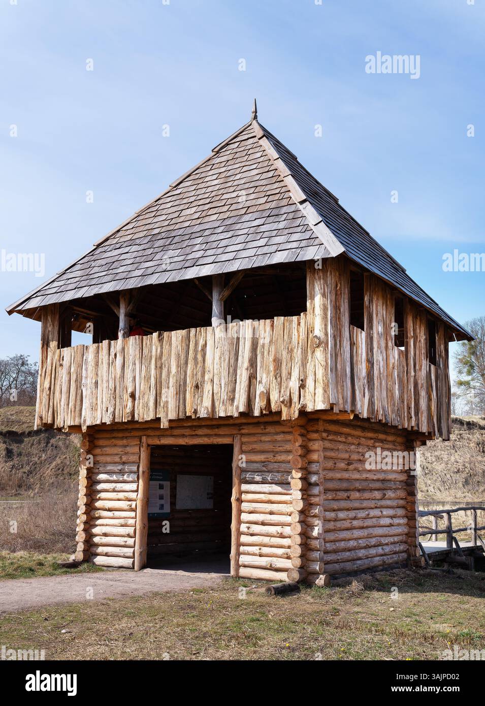 A reconstructed ancient wooden watchtower stands against a clear blue ...