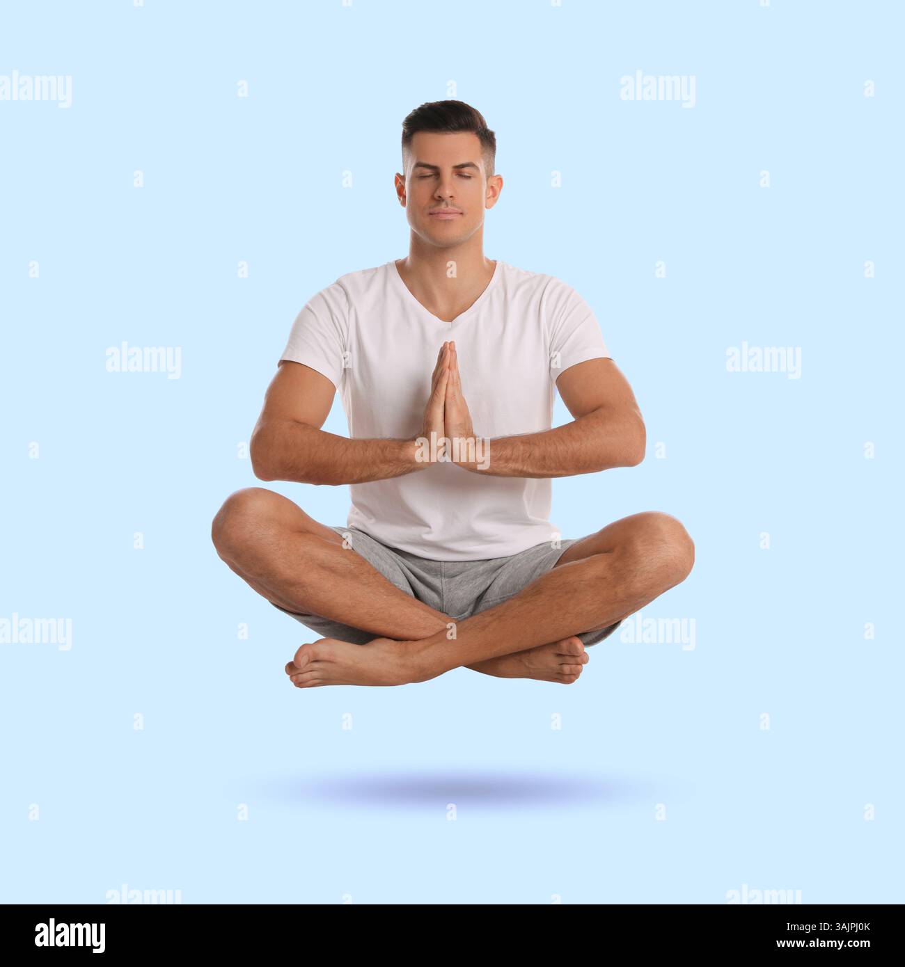 Man levitating during meditation on light blue background. Practicing ...