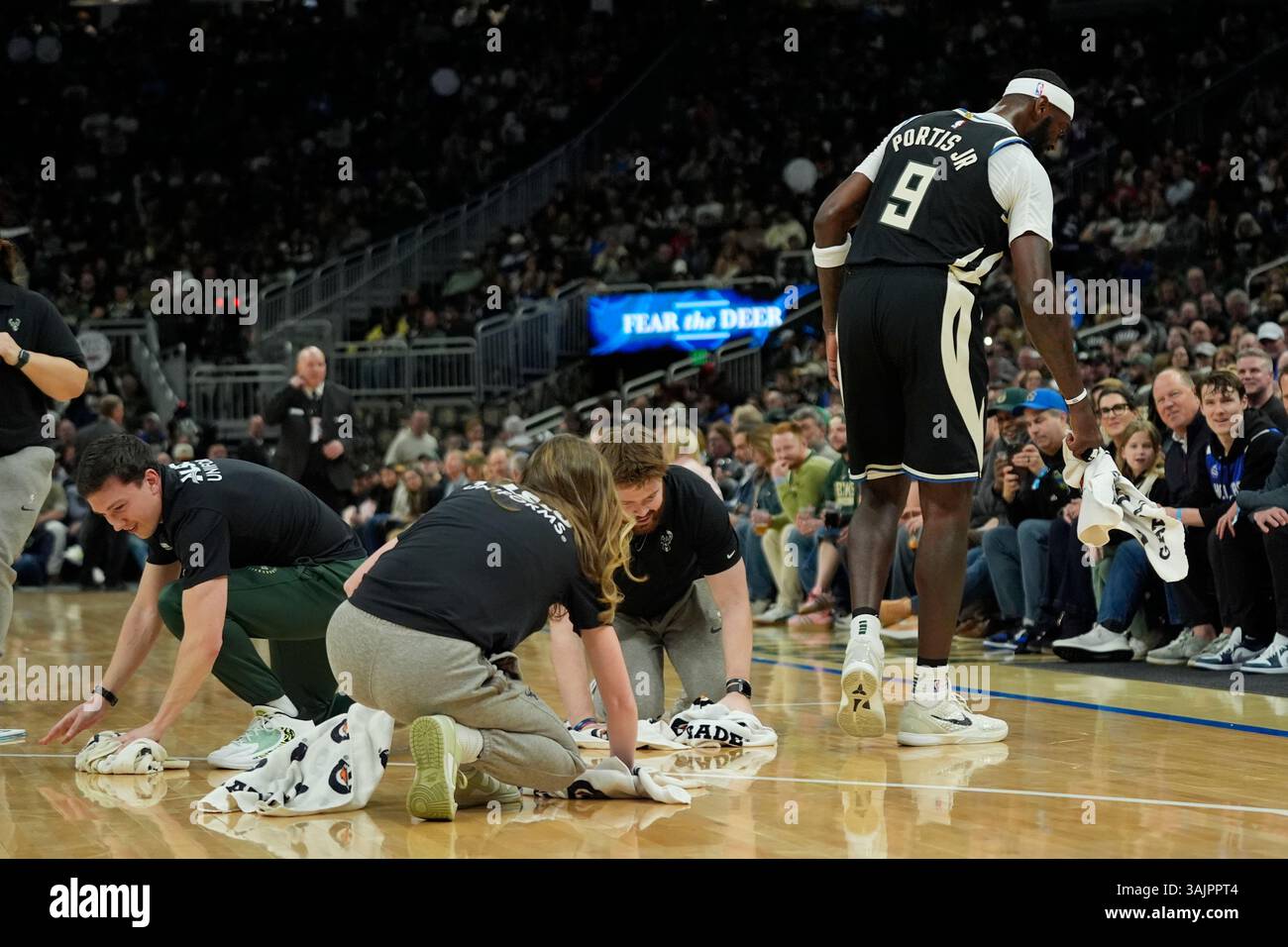 Milwaukee Bucks' Bobby Portis helps clean the floor after a spill ...