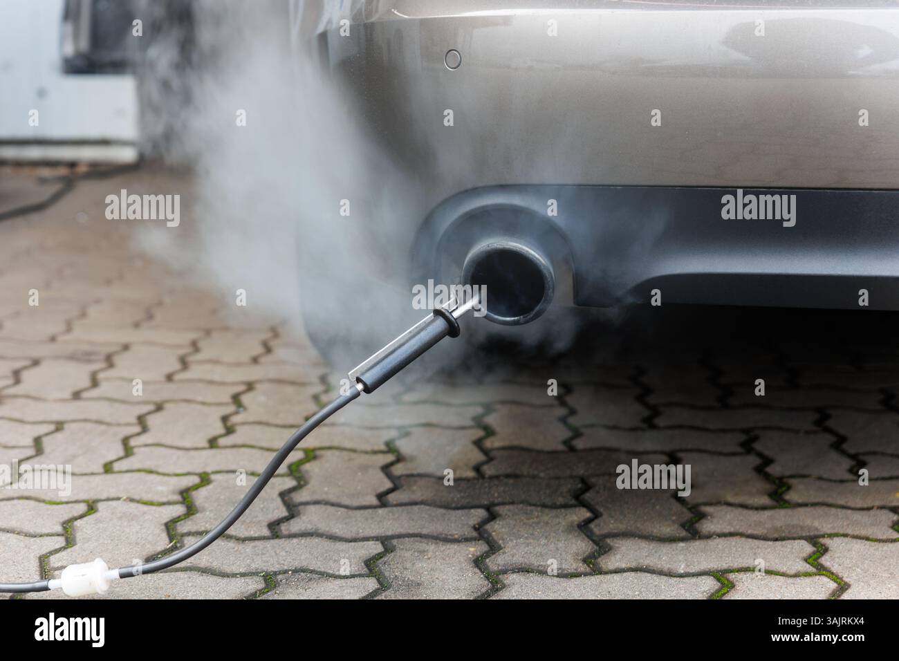 Car exhaust pipe emits dense smoke during emission test on city ...