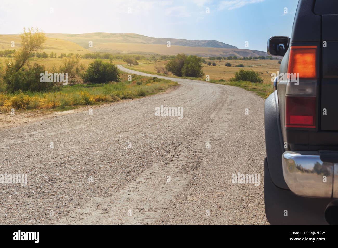 Scenic gravel road winding through hills and grasslands with partial ...