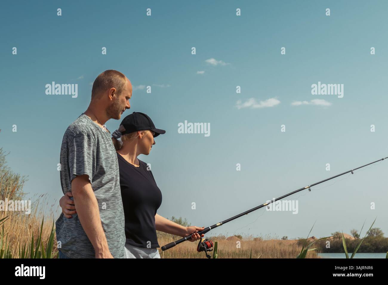 Family couple fishing together on the river bank. Enjoying calm and ...