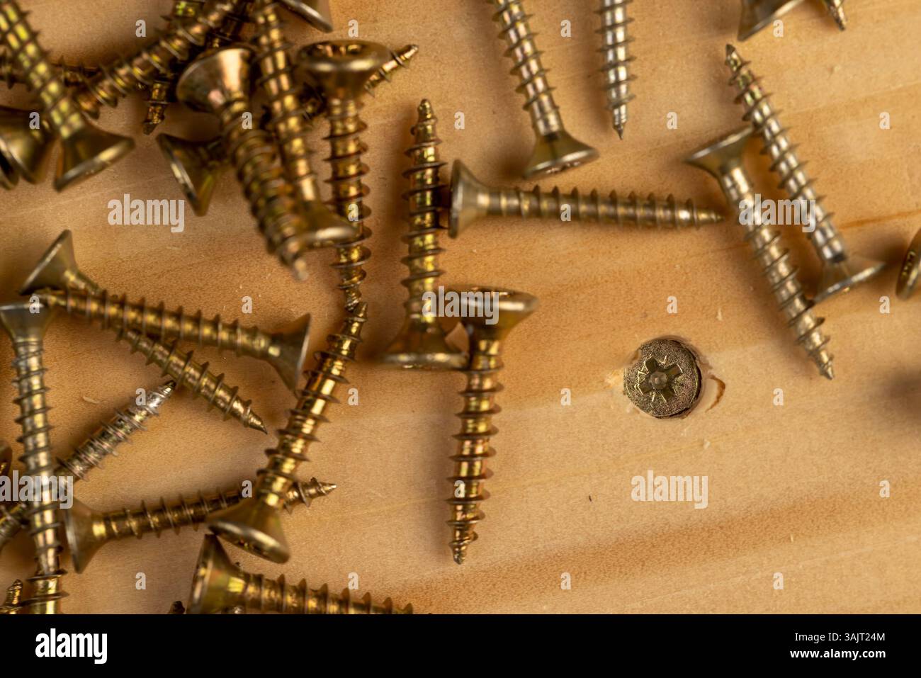 one golden screw twisted into a pine board, a board fixed with a screw ...