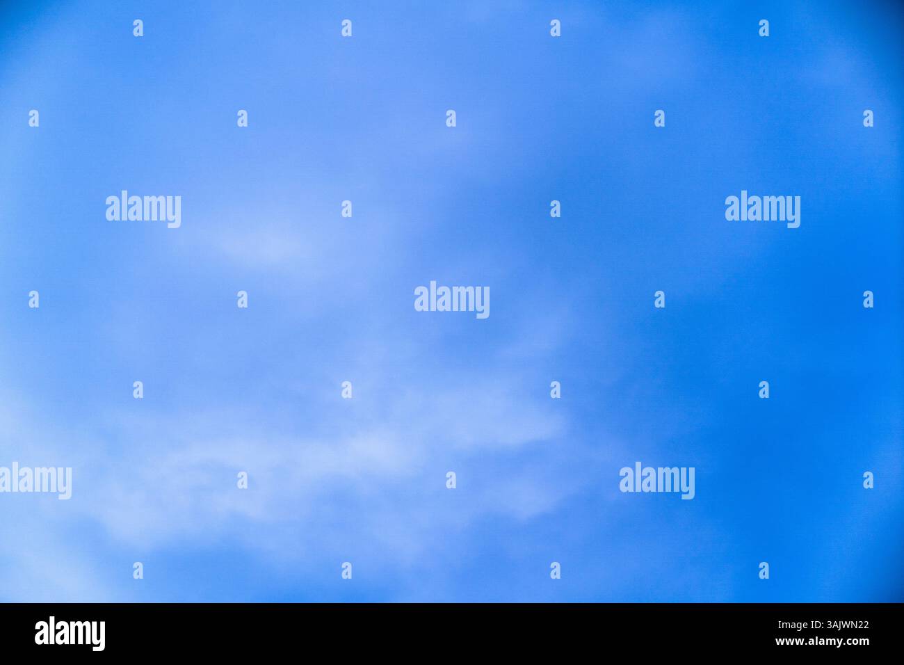 A clear blue sky dominates the scene, showcasing scattered wispy clouds ...