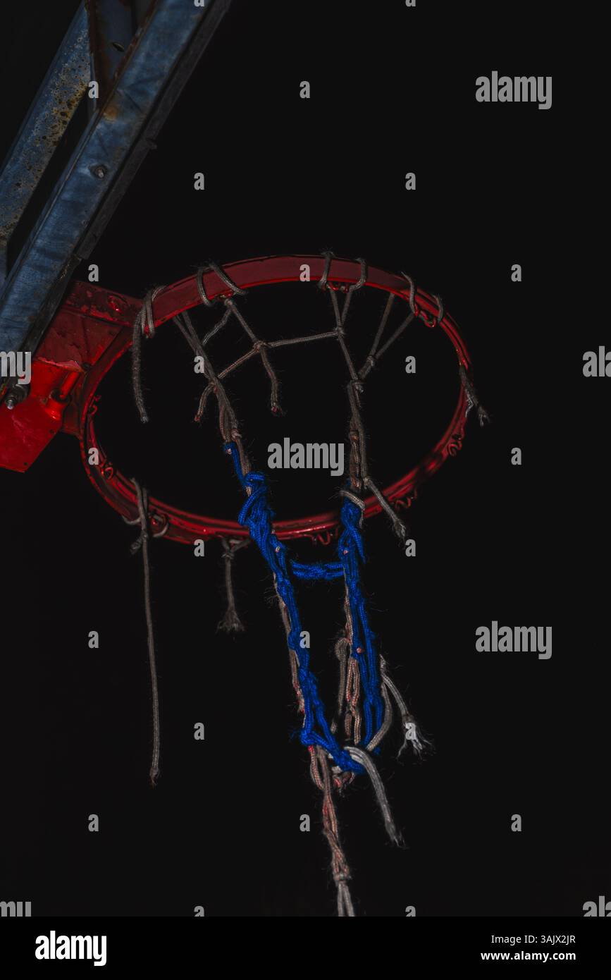 Old rusty outdoor basketball hoop with tattered net photographed at ...