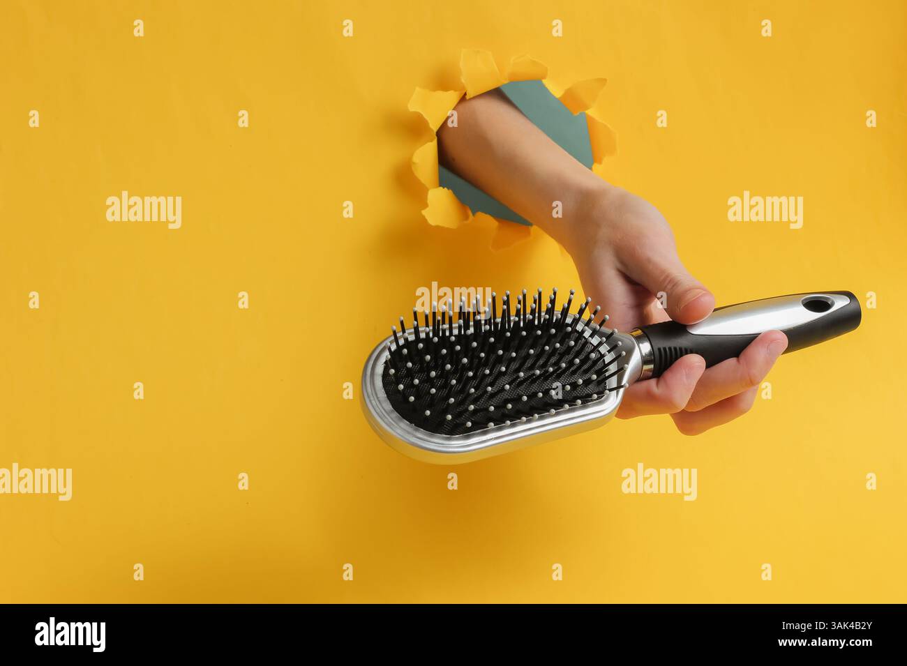 Minimalism fashion concept. Female hand holds comb through a torn hole ...