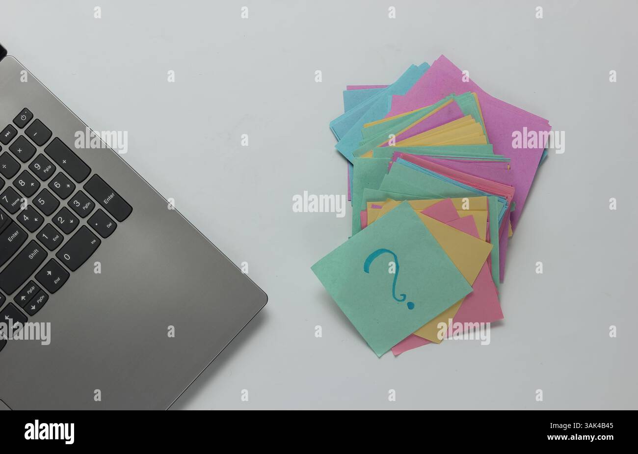 Minimalistic office concept. Lptop and lot of memo papers with question ...