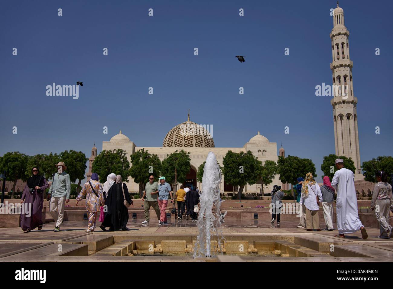 Tourists walk through the courtyard of the Sultan Qaboos Grand Mosque ...