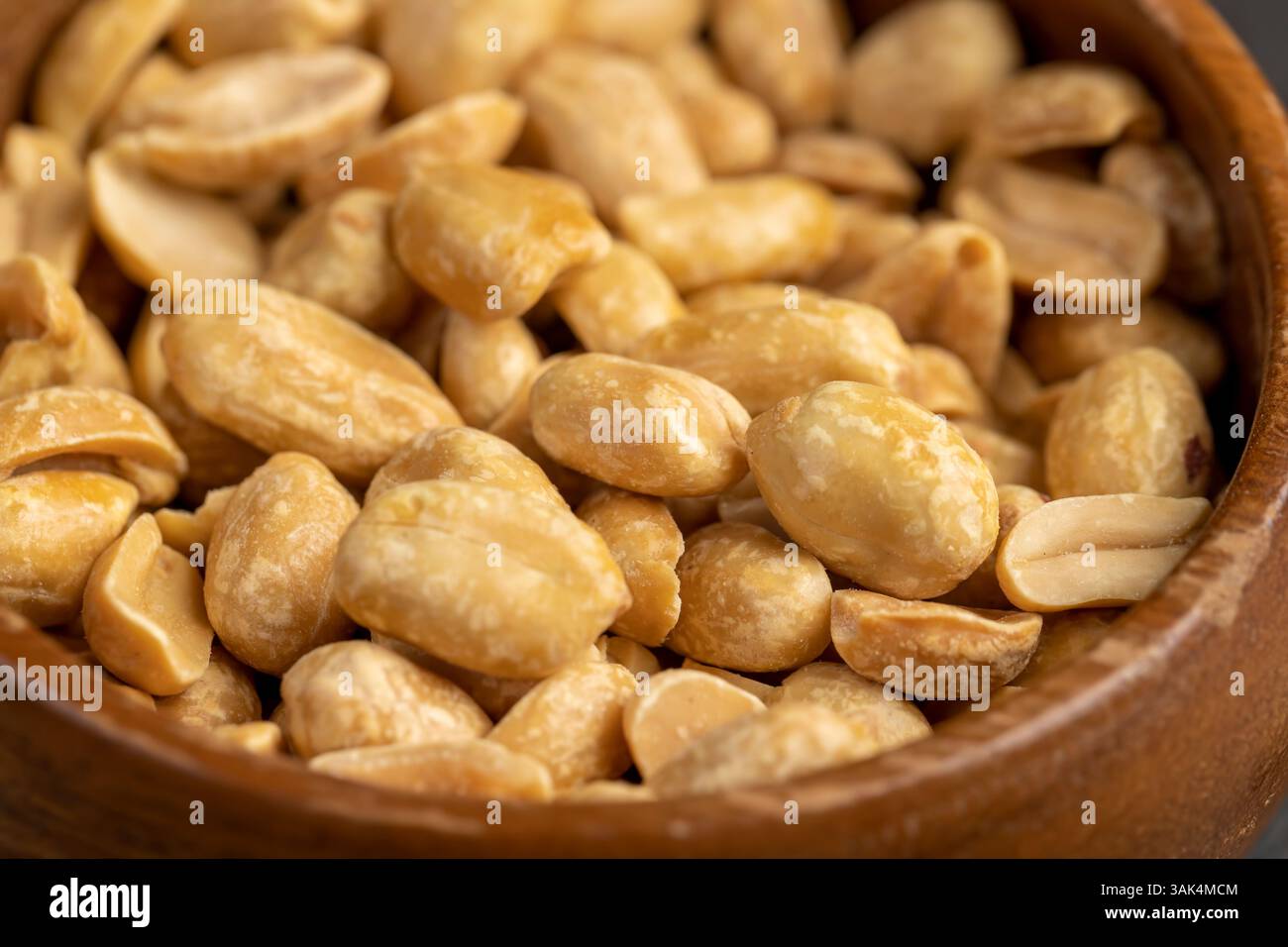peanuts in a wooden bowl, crunchy peanuts without shells on a black ...