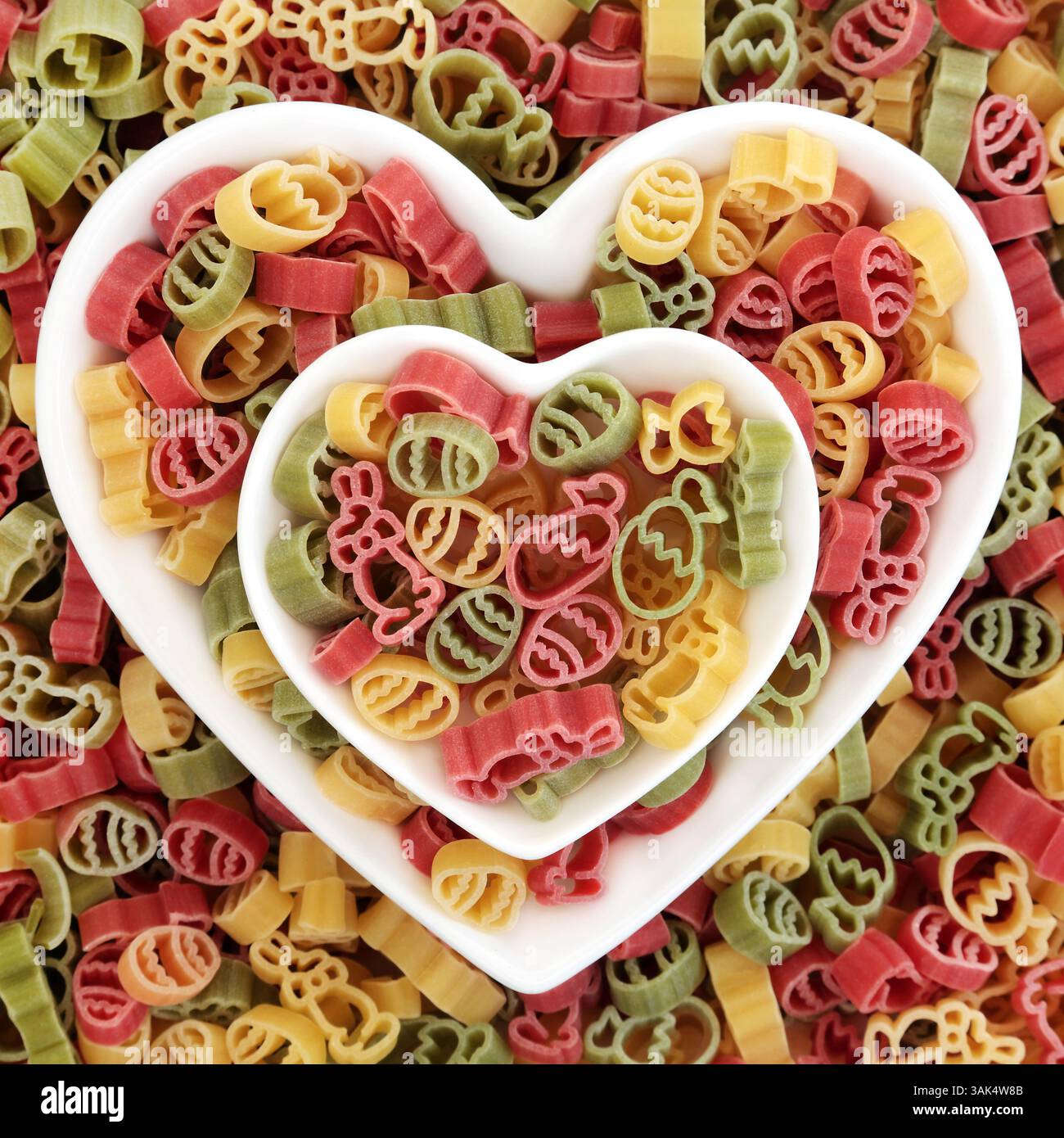 Romantic Italian tricolor dried pasta in heart shape dishes with easter ...