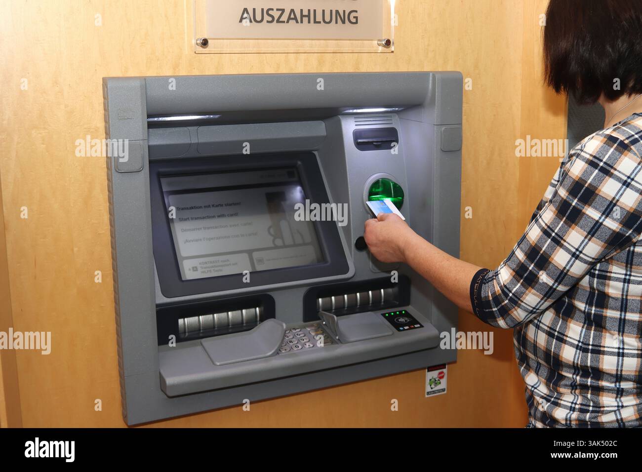 Woman Inserts Debit Card Into An ATM Stock Photo - Alamy