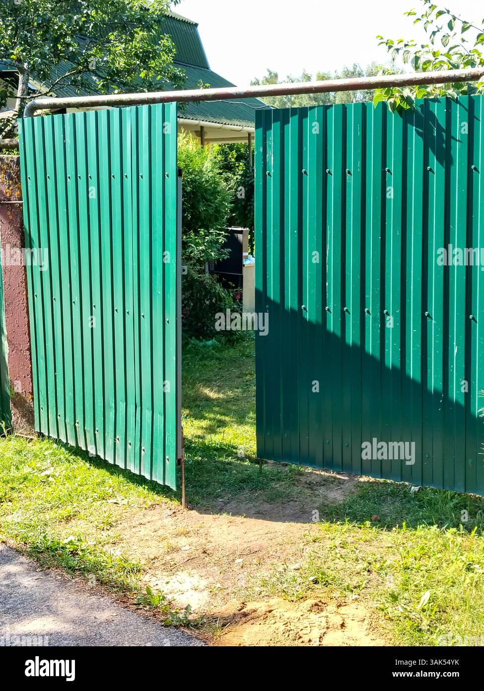 Open metal green gate, made of corrugated metal sheet, in the fence of ...