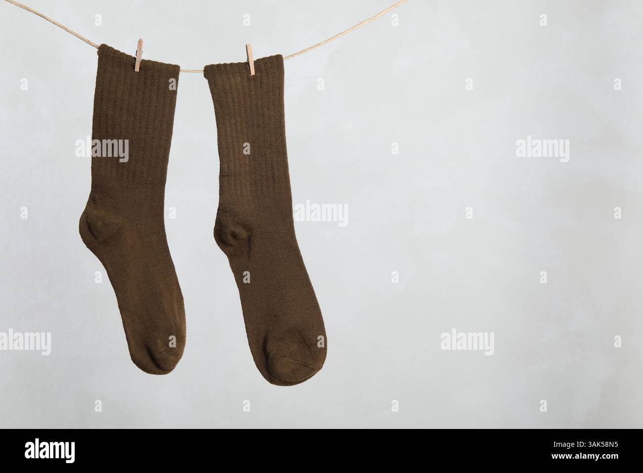 Pair of socks hanging on washing line against light grey background ...