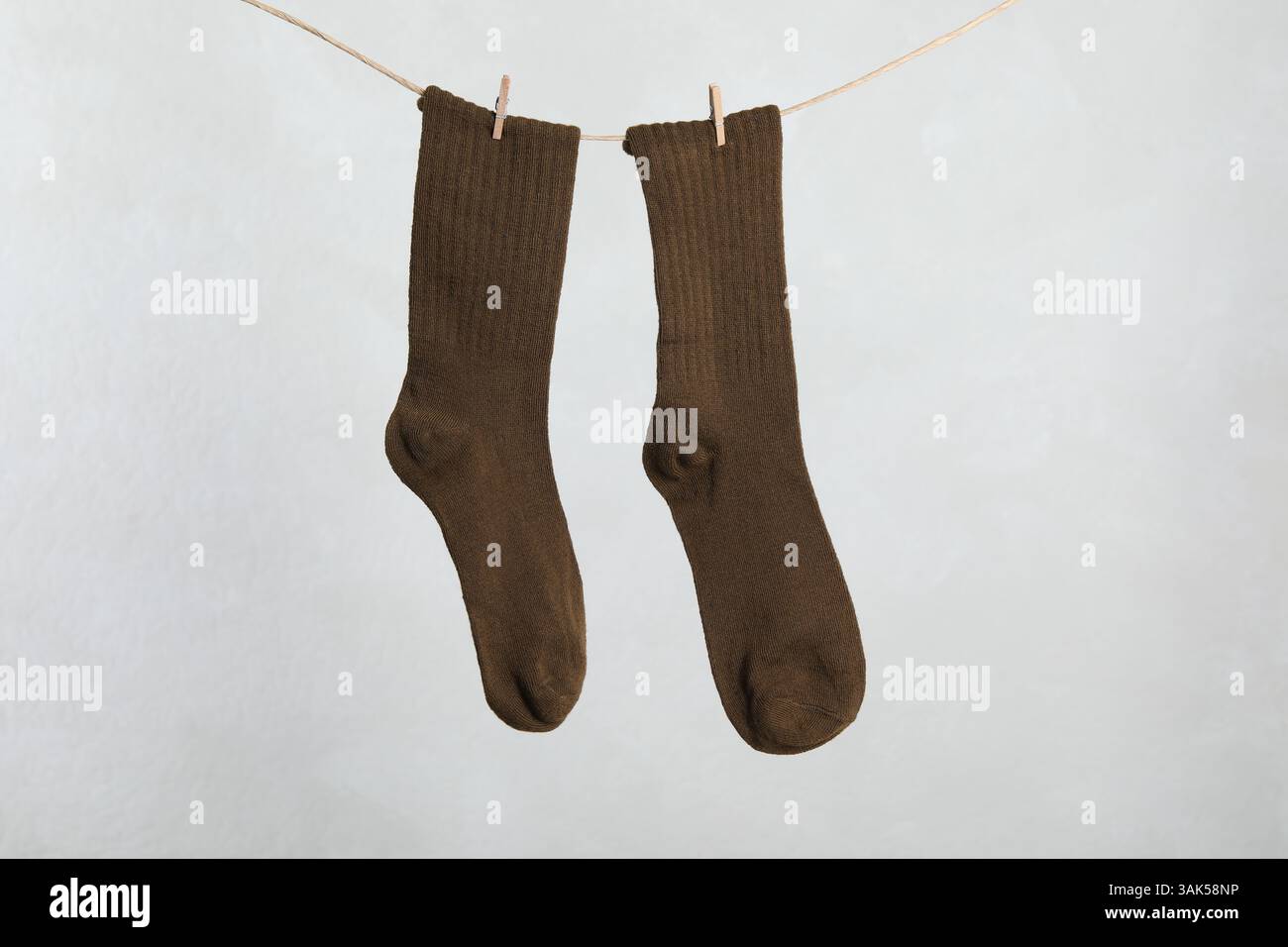 Pair of socks hanging on washing line against light grey background ...
