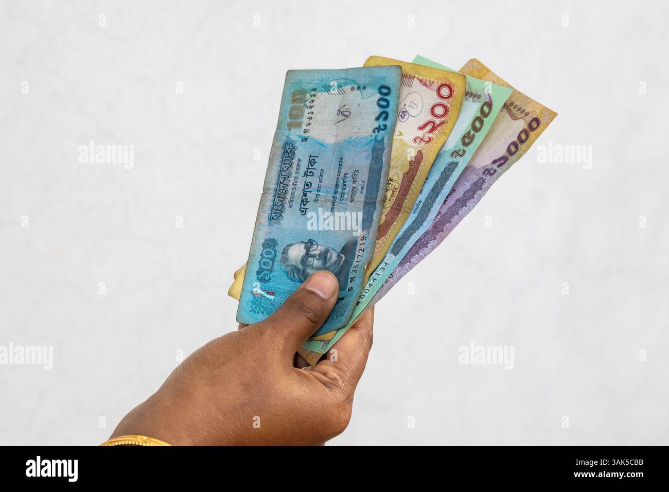 Female hand holding 100, 200, 500, and 1000 Bangladeshi taka banknotes ...