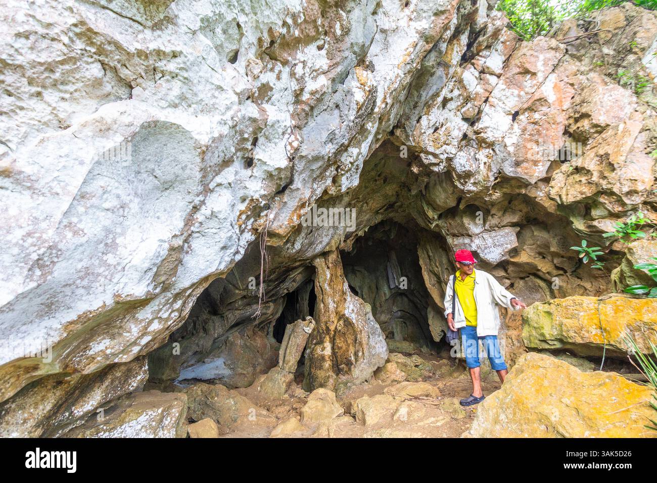 A local cave guide standing at the mouth of Bakwit Cave in Isla ...