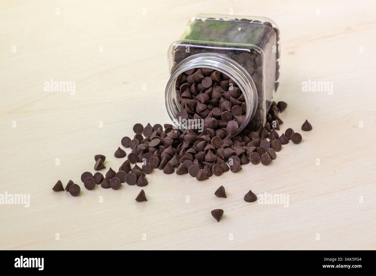 Chocolates scattered on a wooden table from a plastic jar. These round ...