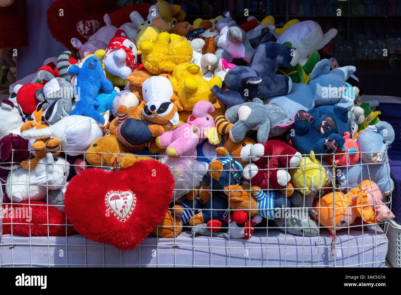 A display stand showcases a bunch of cute, fluffy animal soft toys in various vibrant colors at ...