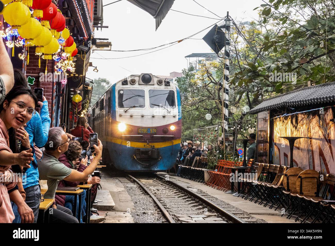 Tourists watch and take photos of the train arriving at Train Street in ...