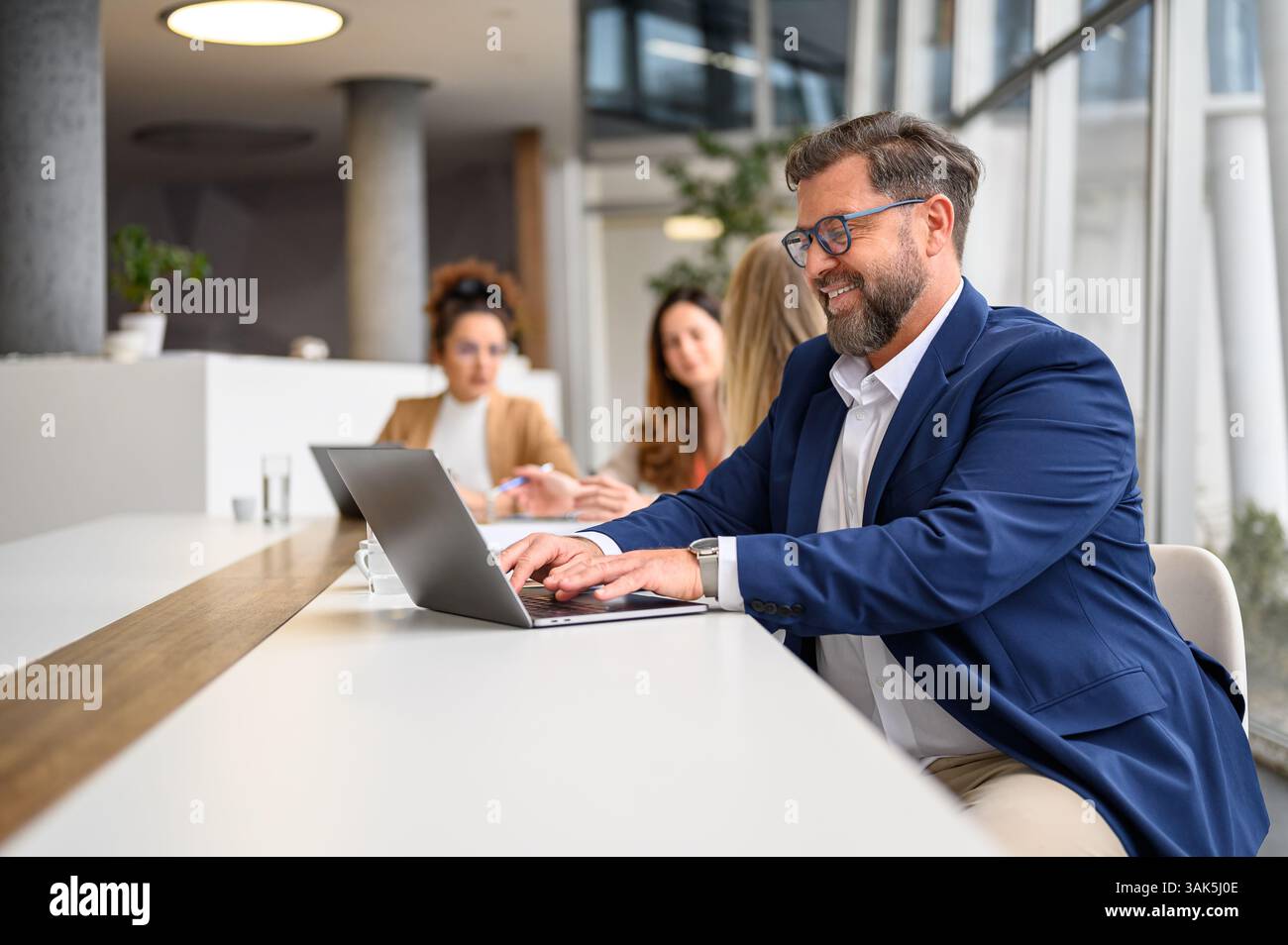 Focused male lawyer working on laptop in boardroom while female ...