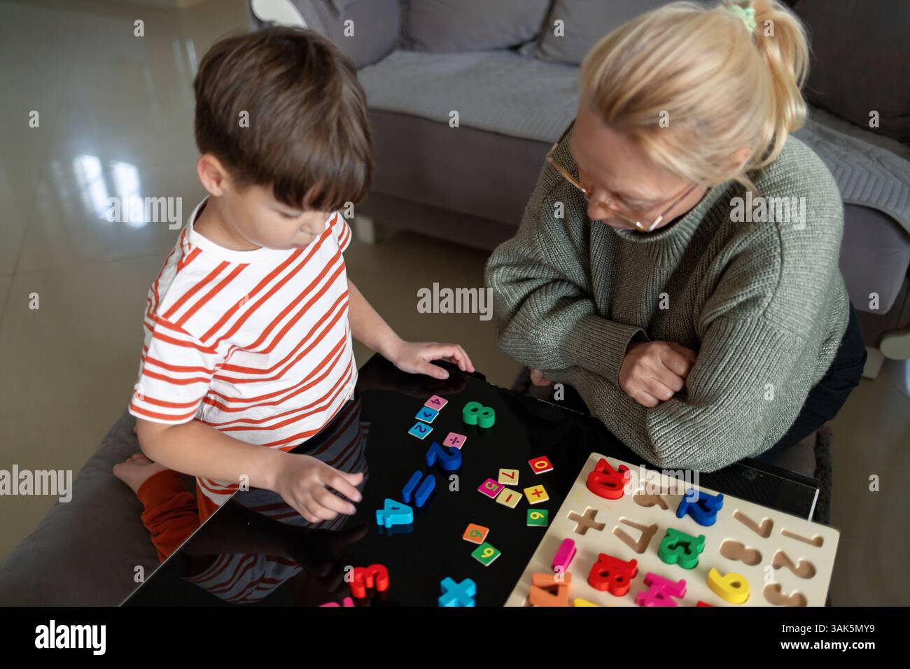 Child learning to count with wooden numbers and adult guidance at home ...