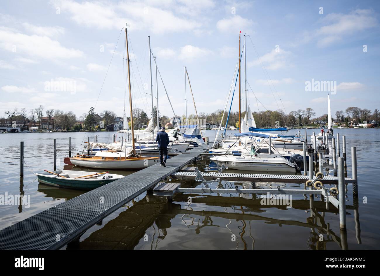 12 April 2025, Brandenburg, Zeuthen: A man walks across a jetty with ...