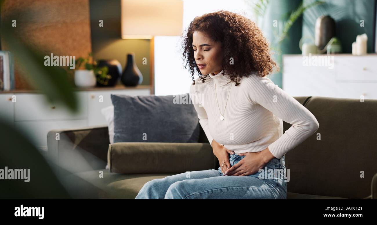 Sofa, woman and hands on stomach for pain, menstrual cycle and ...