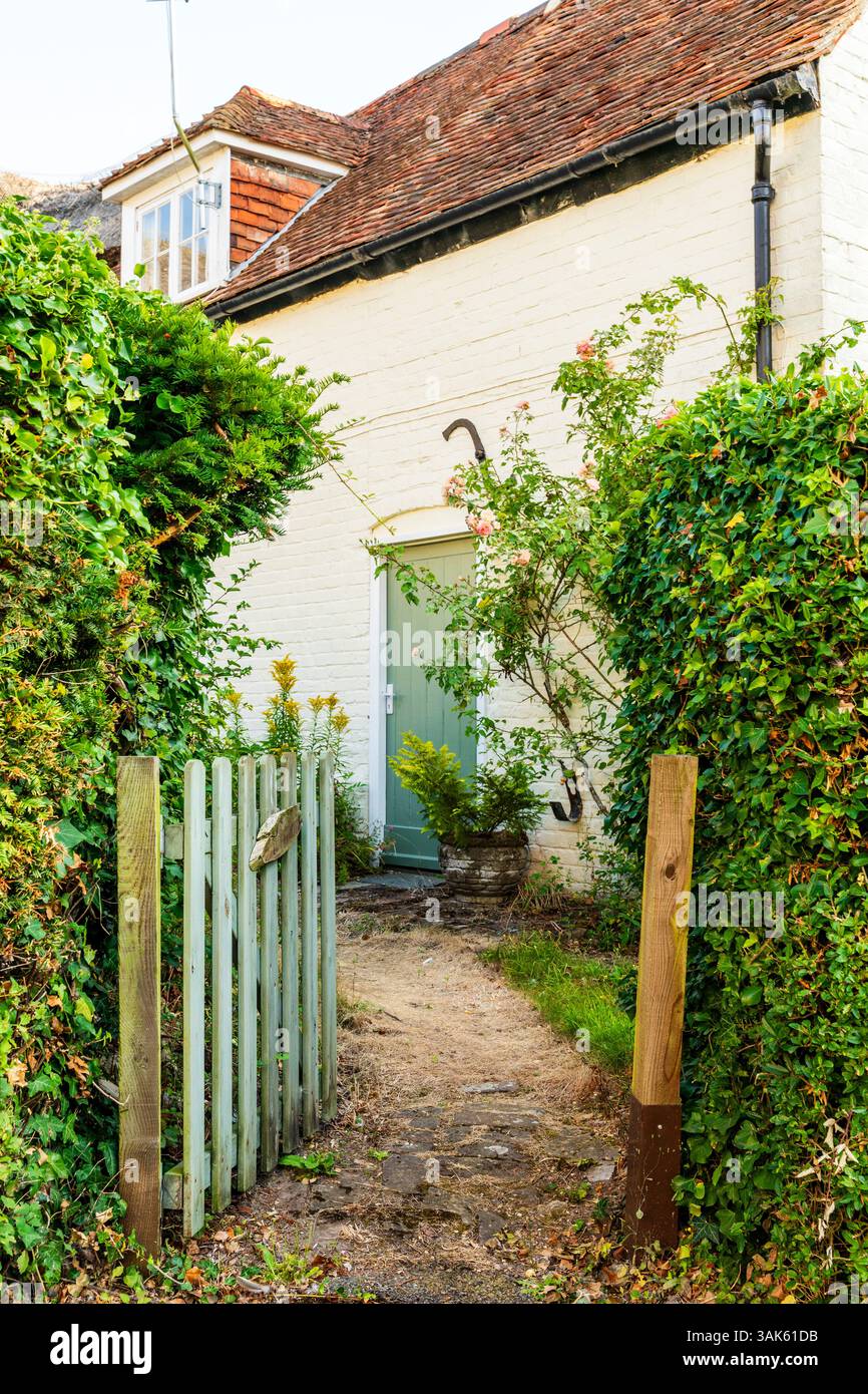 Open green garden gate with pathway leading to a green front door of a ...