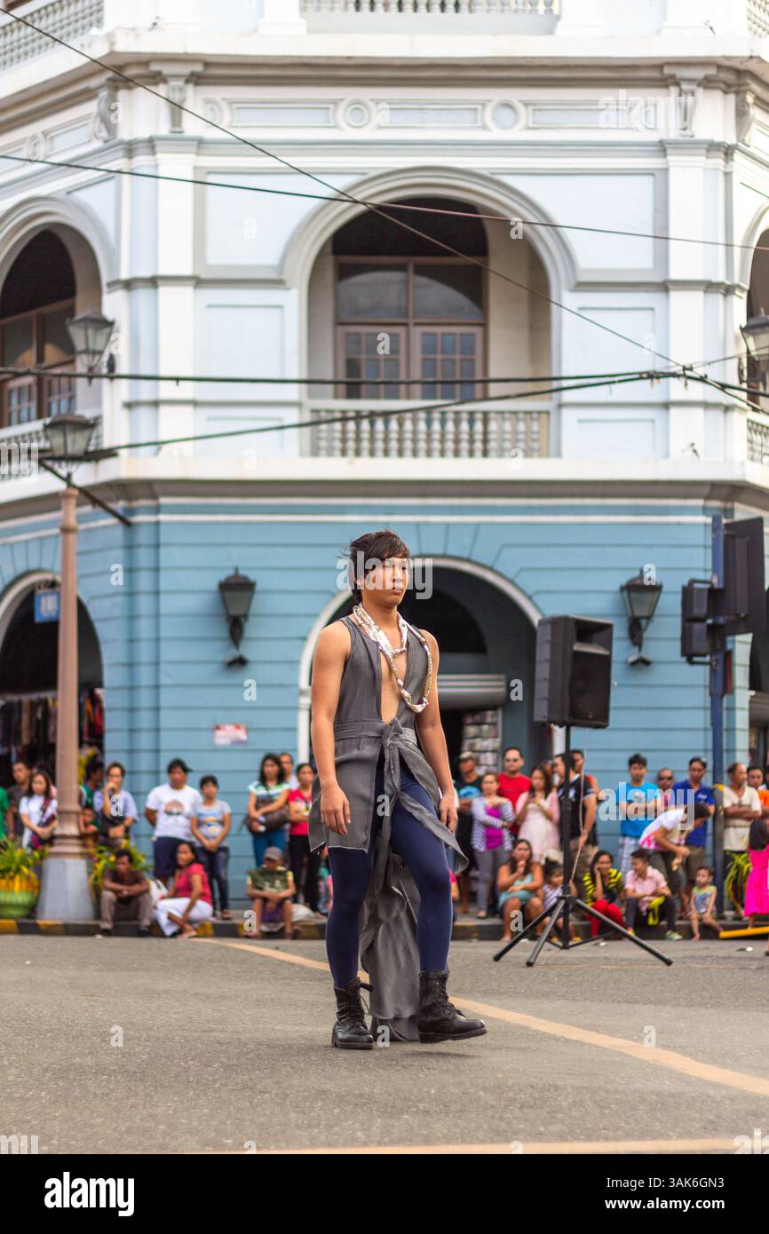 A male fashion model walks confidently along a street in Iloilo City ...
