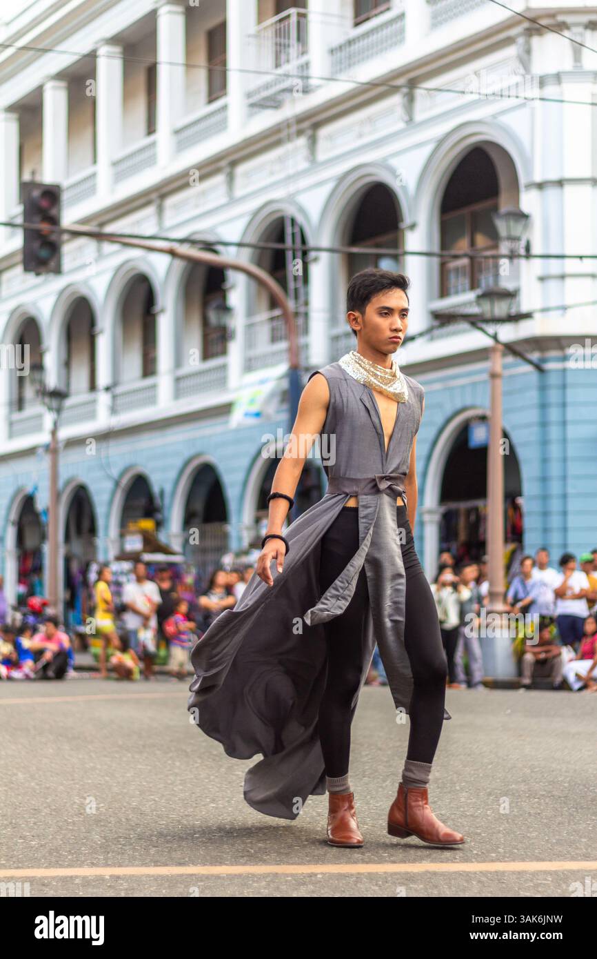 A male fashion model walks confidently along a street in Iloilo City ...