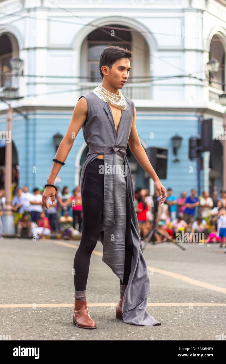 A male fashion model walks confidently along a street in Iloilo City ...