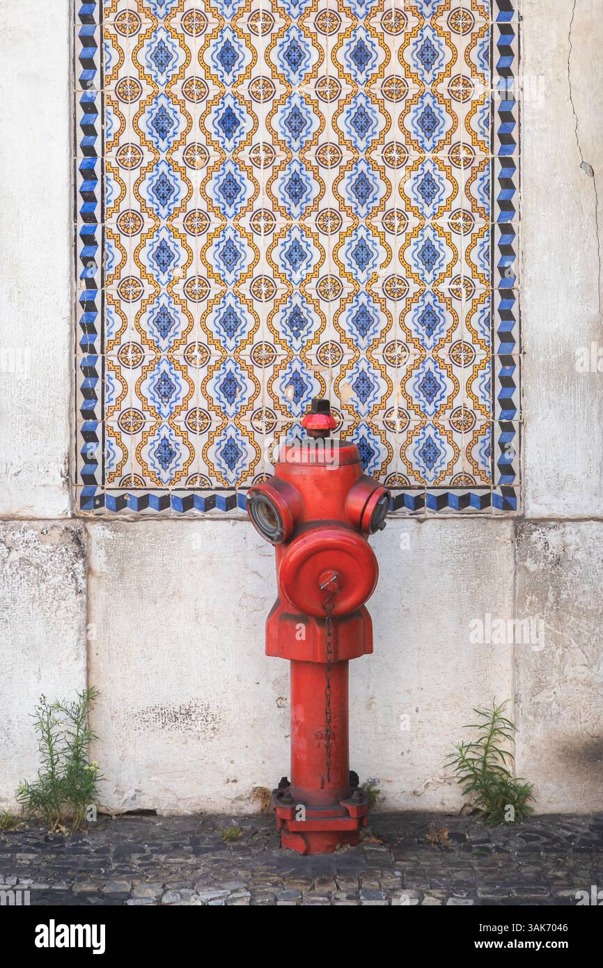 A weathered red fire hydrant stands on a cobblestone sidewalk in Lisbon ...