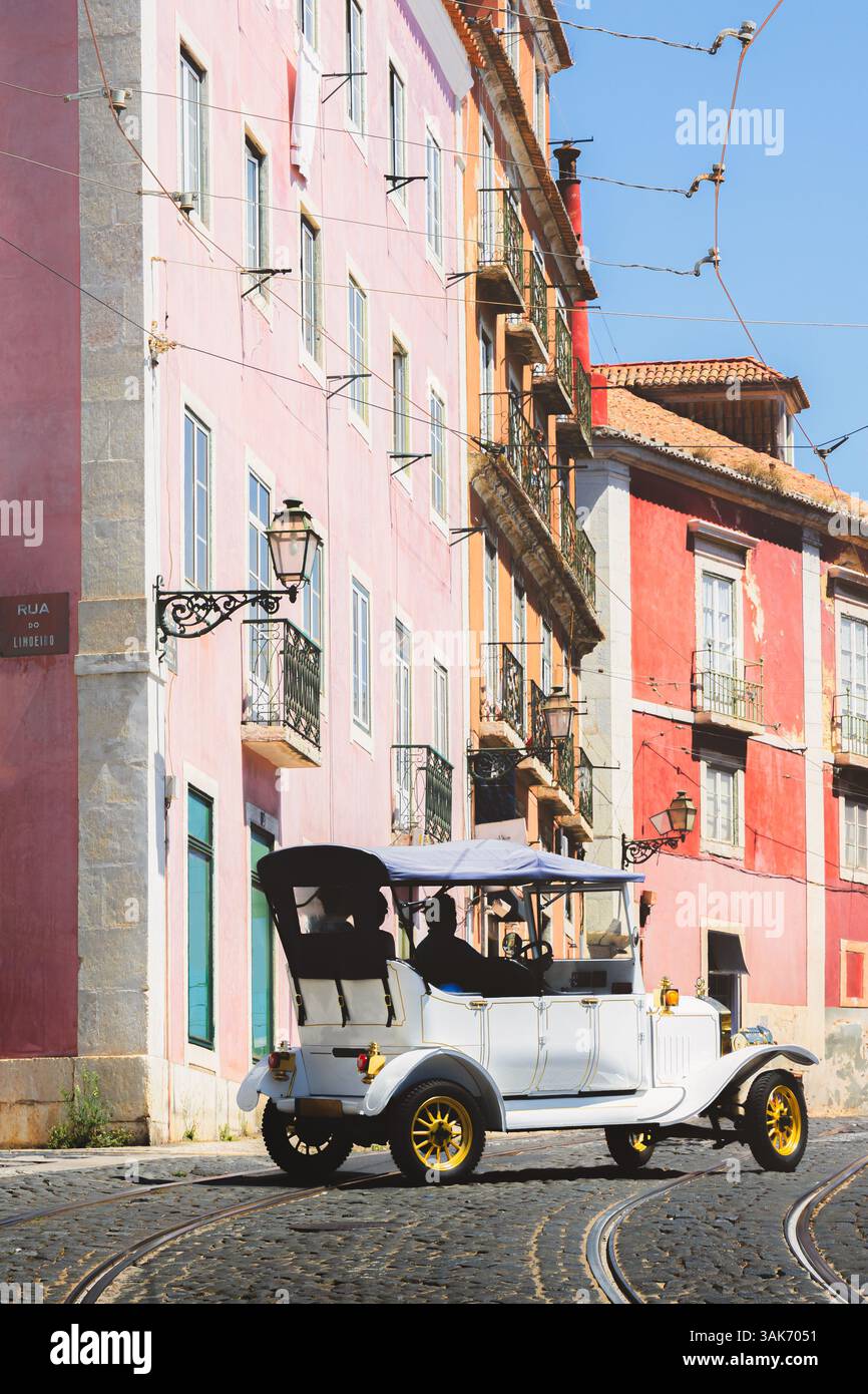A vintage classic car navigates the cobblestone street of Lisbon ...