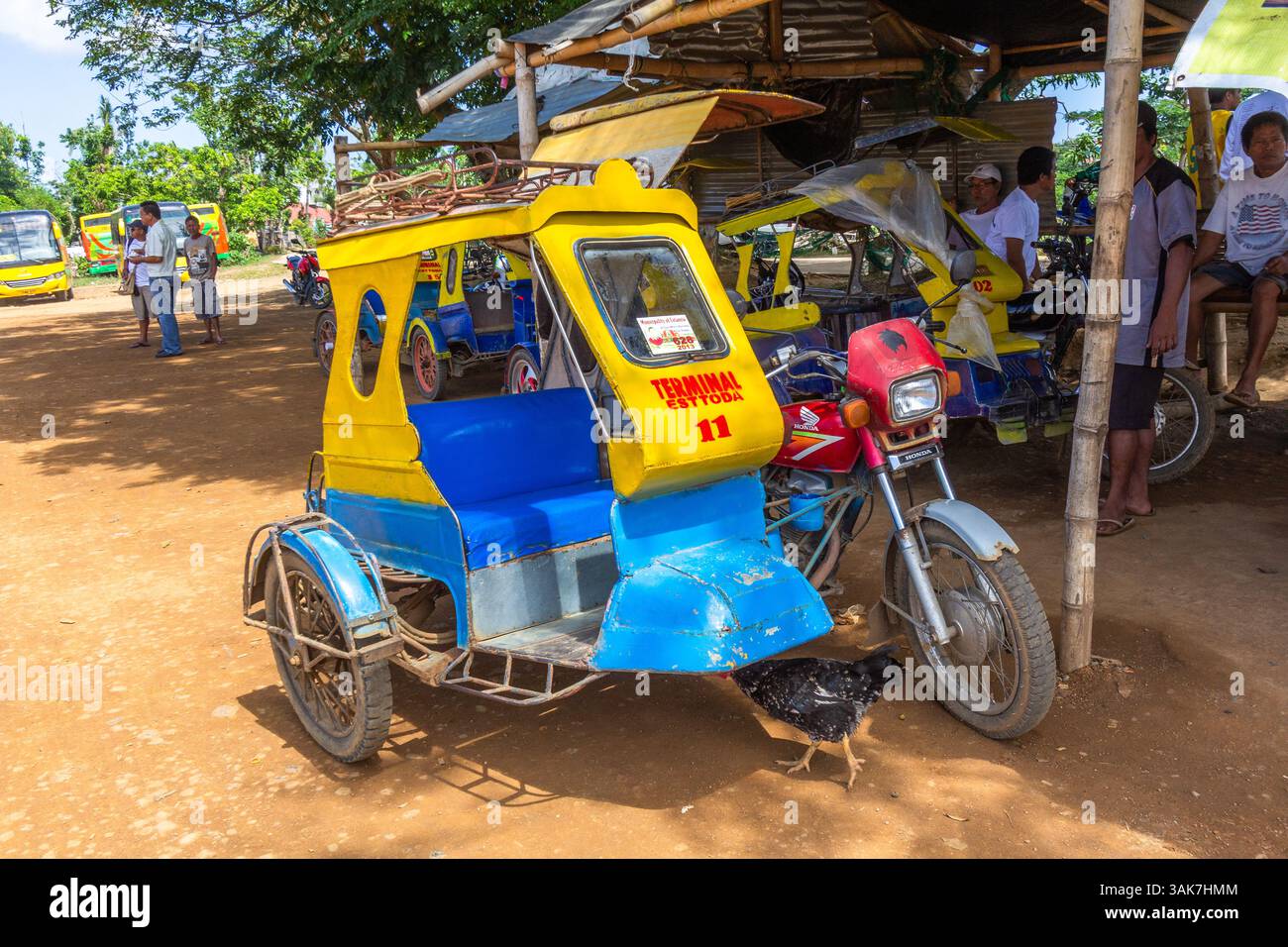 Blue and yellow tricycles wait at a busy terminal in Iloilo, a common ...