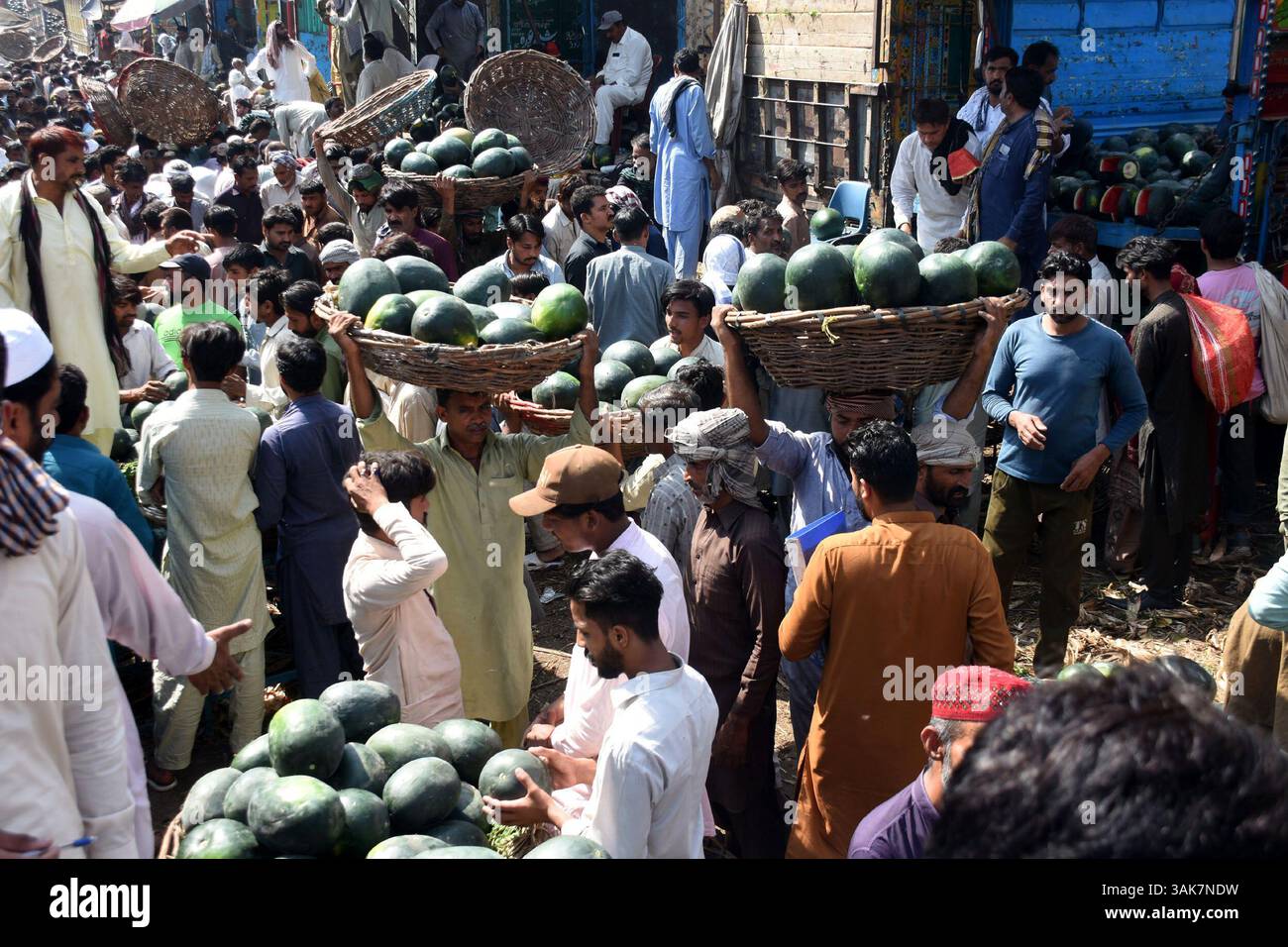 Lahore. 12th Apr, 2025. People carry watermelons at a wholesale market in Lahore, Pakistan on ...