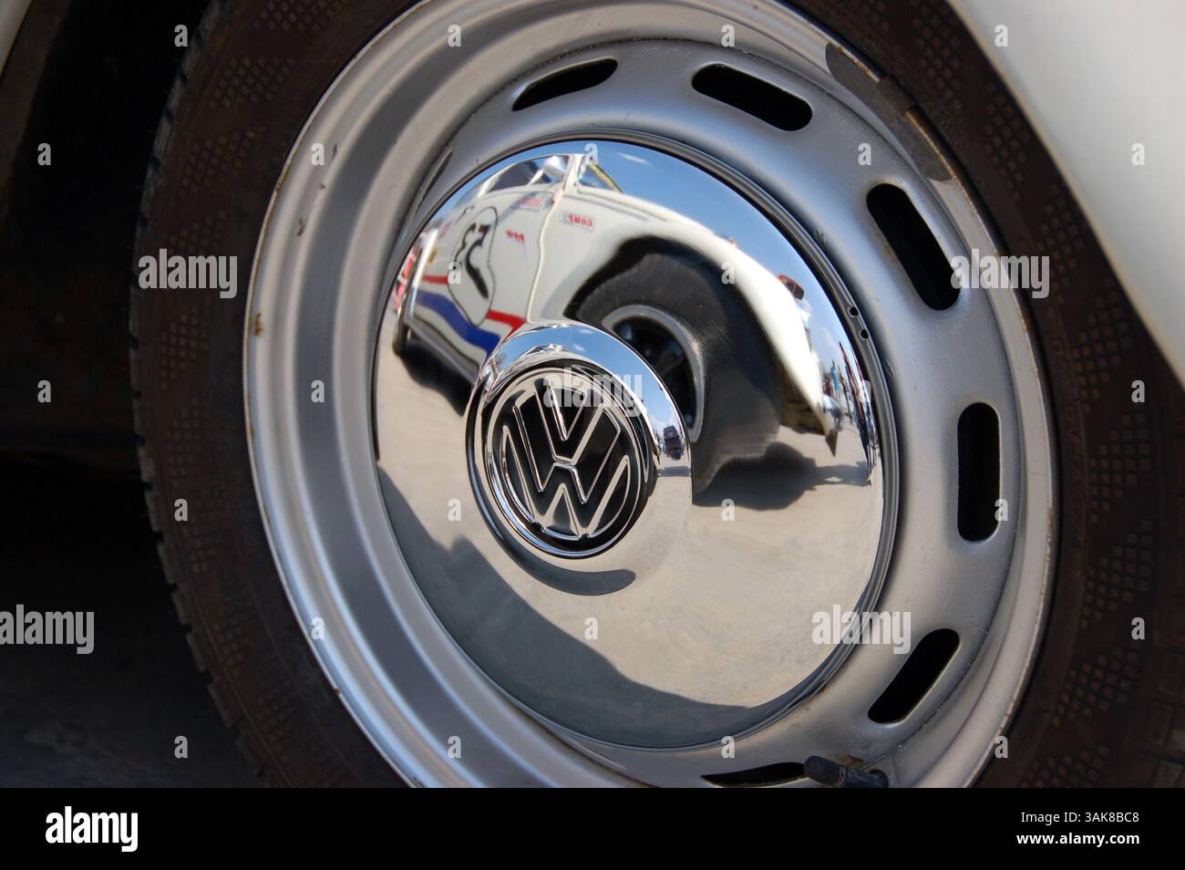 Close-up of a Volkswagen Beetle wheel with a chrome hubcap reflecting ...
