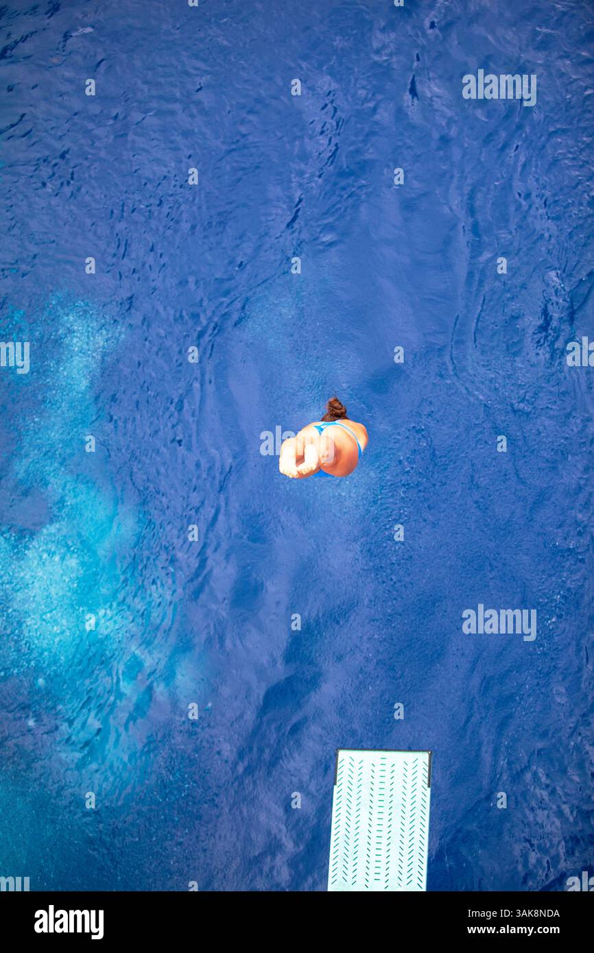 Woman diving into swimming pool from diving board Stock Photo - Alamy
