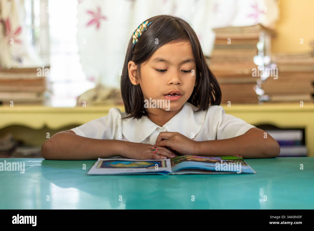 A young Filipino student reading a children's book inside a public ...