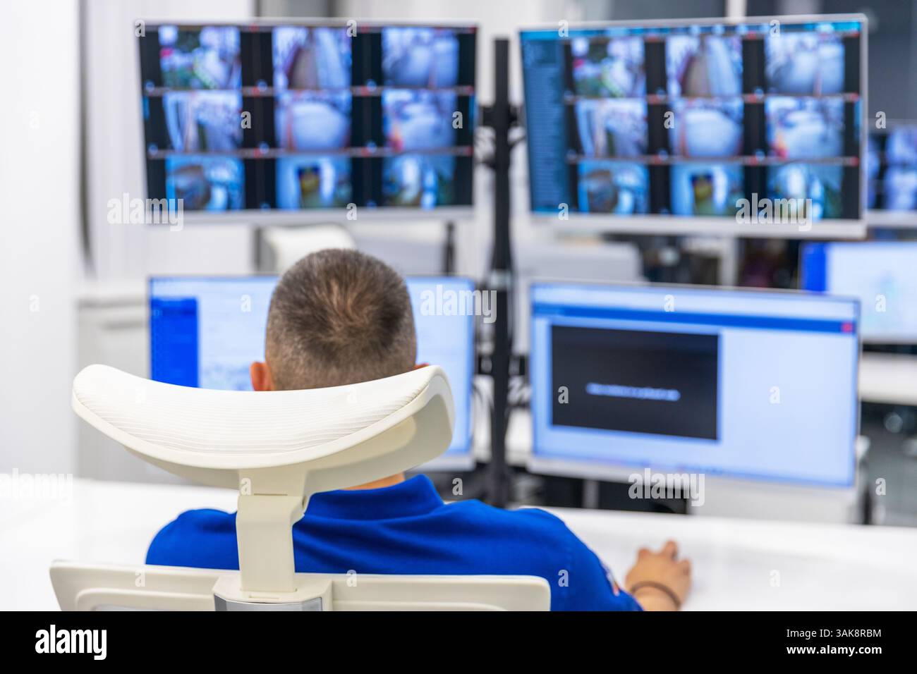 Security personnel monitoring multiple surveillance cameras on large ...